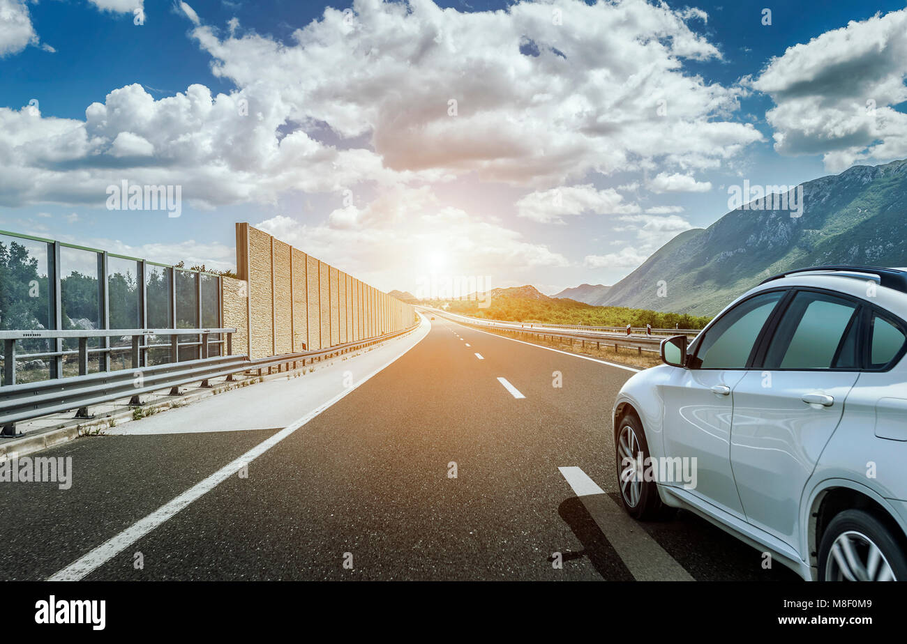 A white car rushing along a high-speed highway in the sun Stock Photo ...