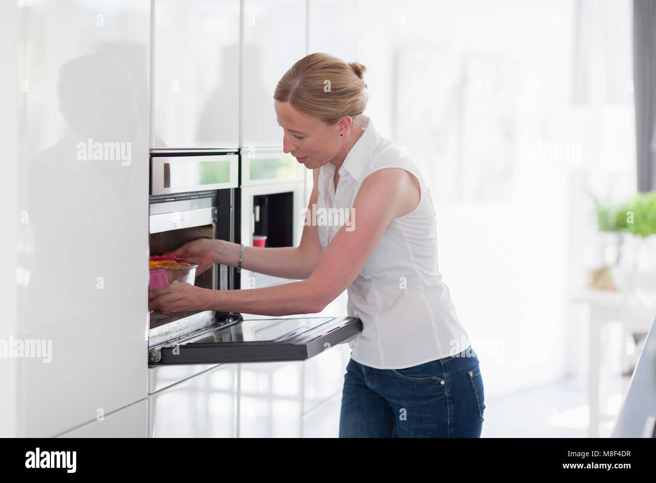 Woman using oven in kitchen Stock Photo - Alamy