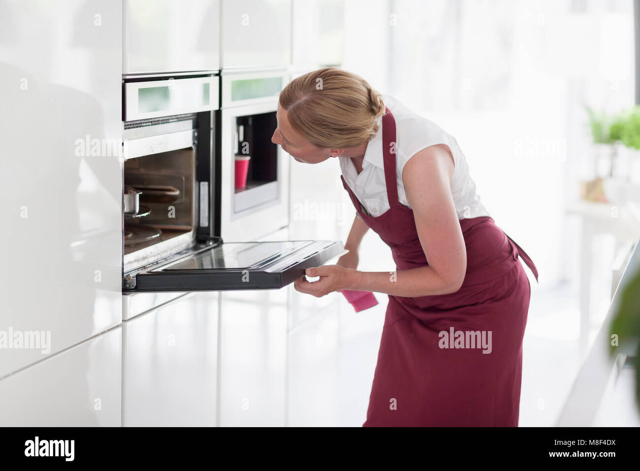 Woman using oven in kitchen Stock Photo - Alamy