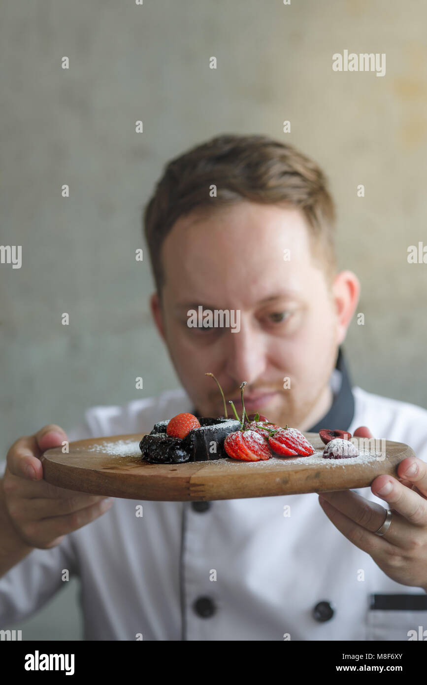 Closeup of a concentrated male pastry chef decorating dessert in the ...
