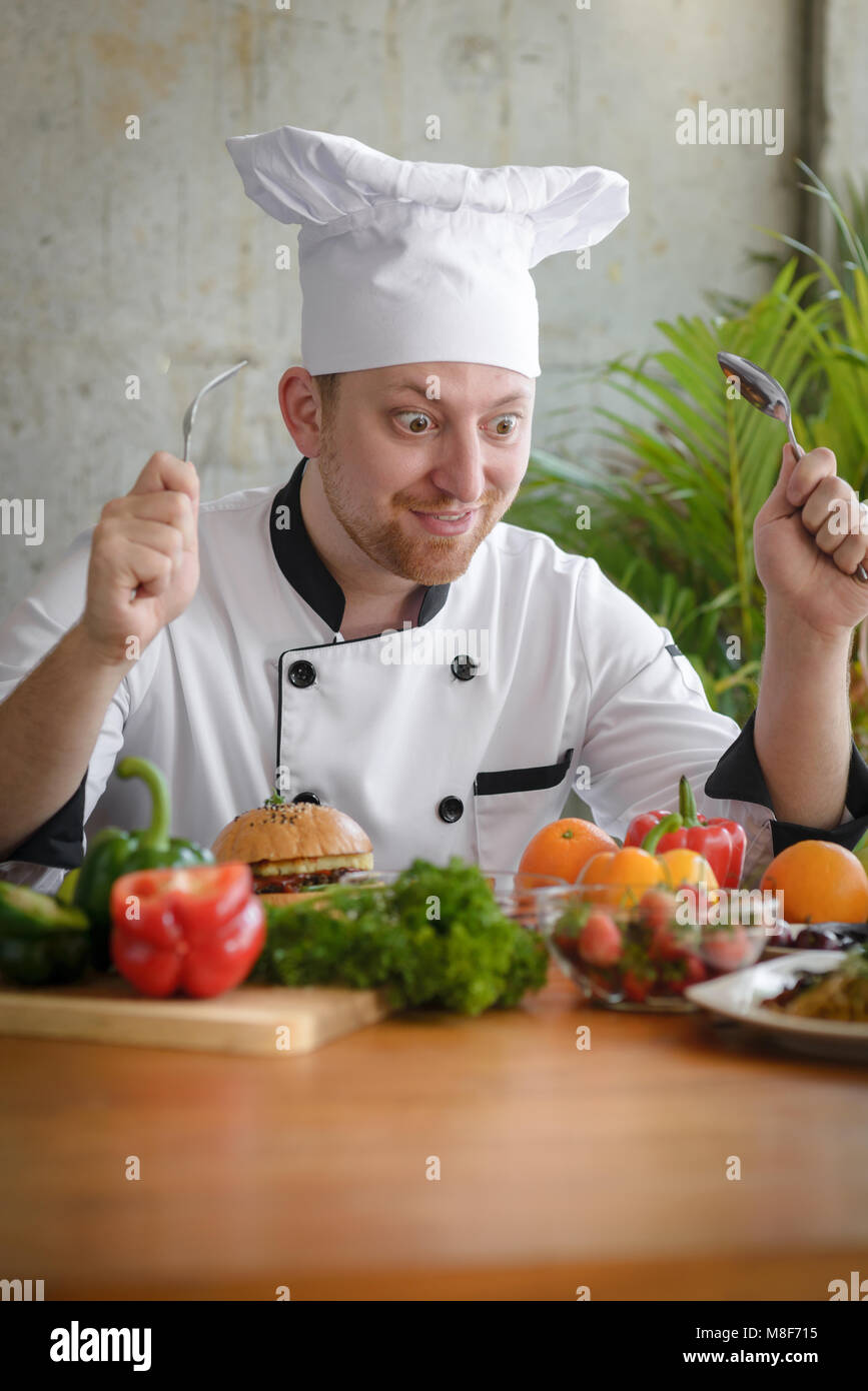 Stressed professional chef holding spoon and fork with vegetables on ...