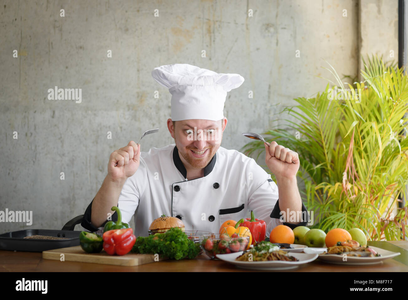 Stressed professional chef holding spoon and fork with vegetables on ...
