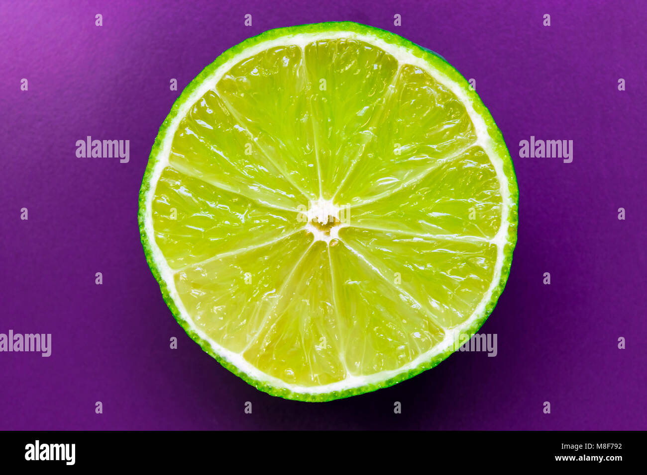 Lime, cutted in the half and placed cutted side up on purple background ...