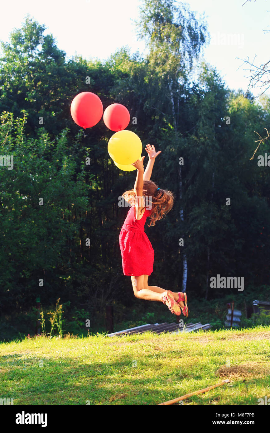 Happy child jumping with colorful toy balloons outdoors. Smiling kid ...