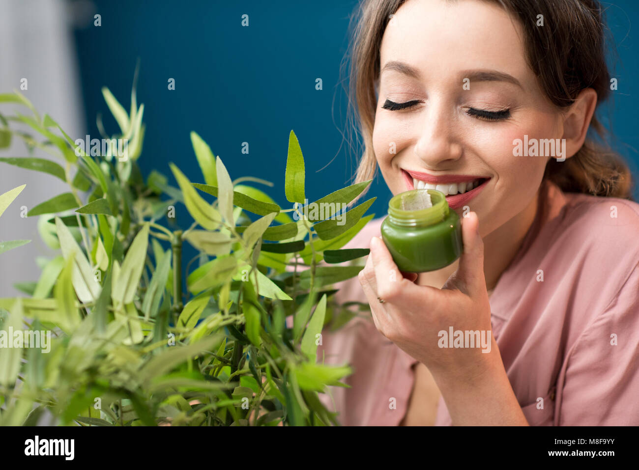 Woman with cosmetics and green plant indoors Stock Photo - Alamy