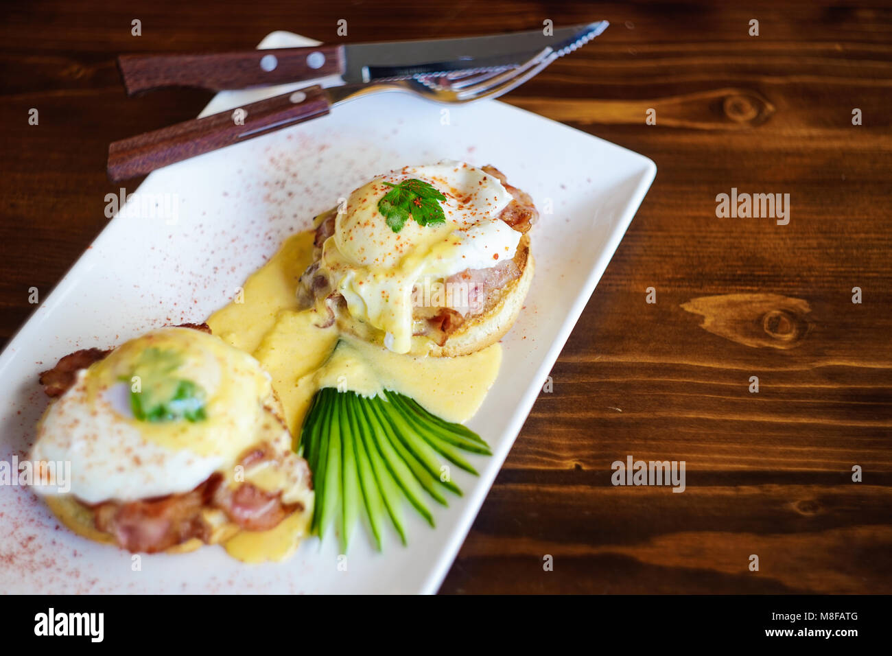 Rustic lunch set with benedict eggs and cucumber salad on dark wooden ...