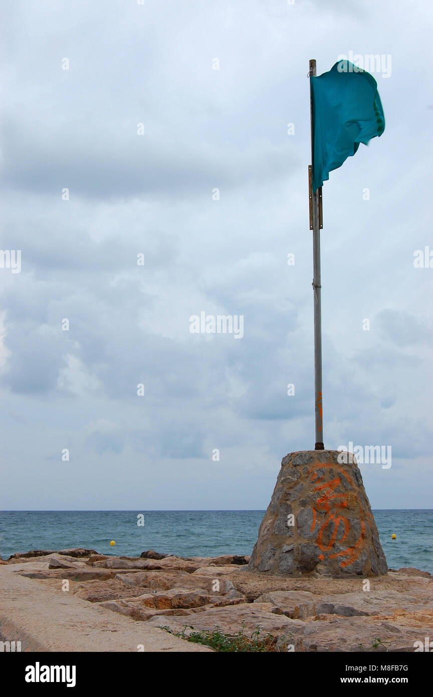 Green beach flag in good weather with sea background in the coast of ...