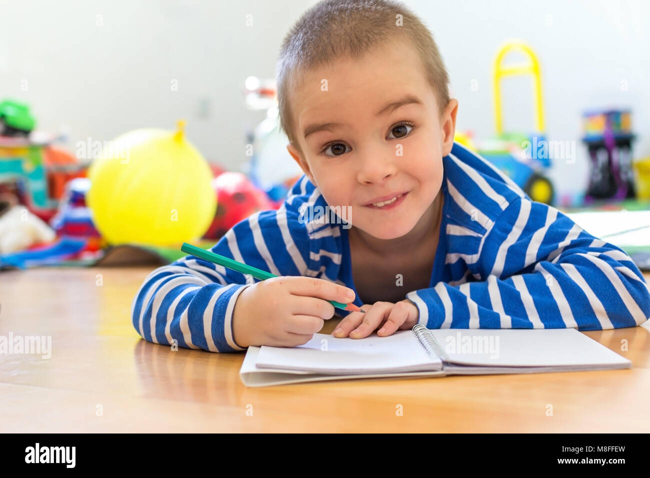 Little child boy writing something in notebook on the floor Stock Photo ...