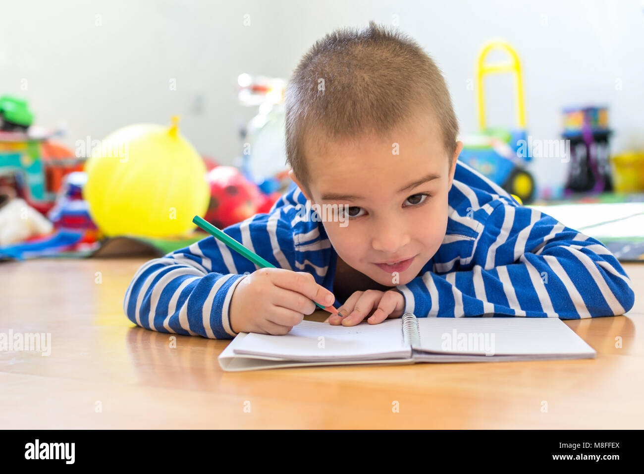 Little child boy writing something in notebook on the floor Stock Photo ...
