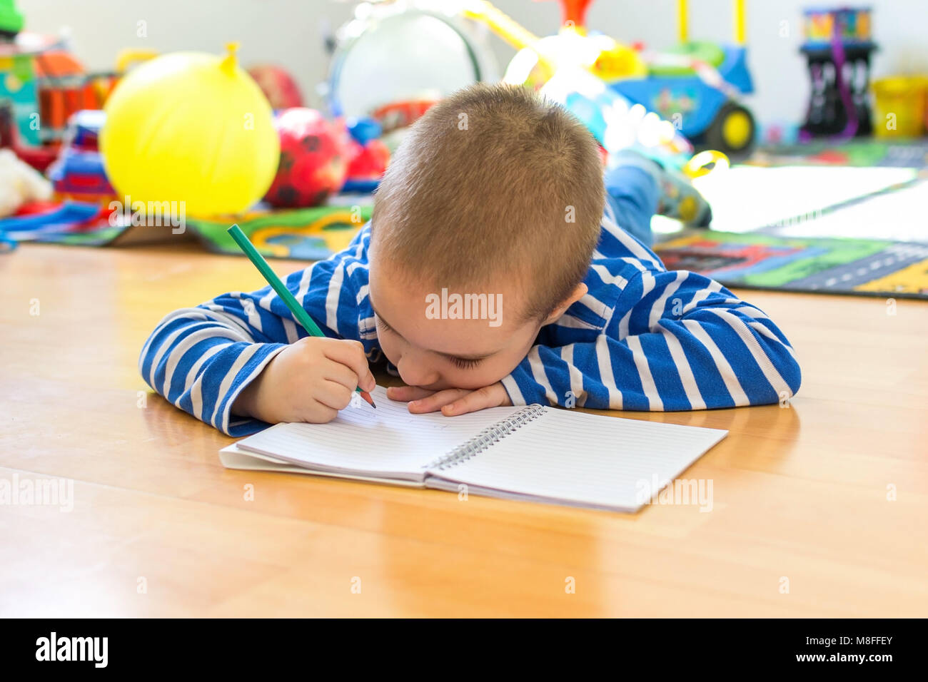 Little child boy writing something in notebook on the floor Stock Photo ...
