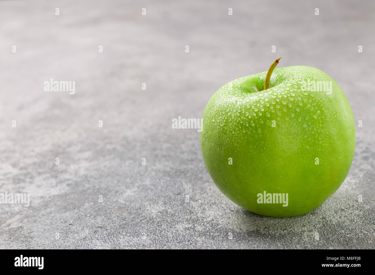Juicy ripe green Apple with water drops on a concrete background ...
