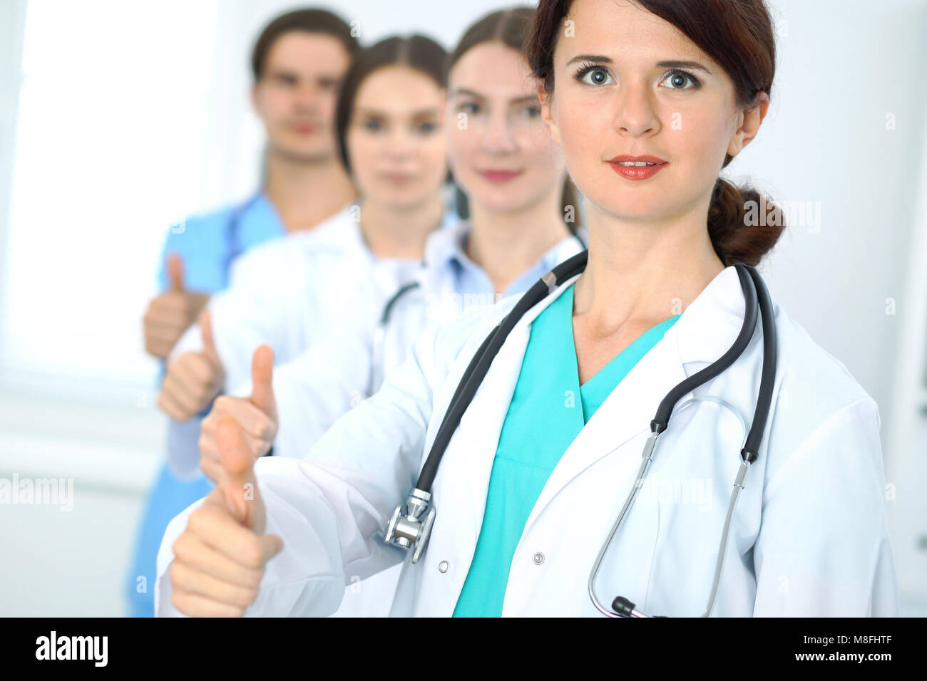 Group of doctors showing OK or approval sign with thumb up. High level ...