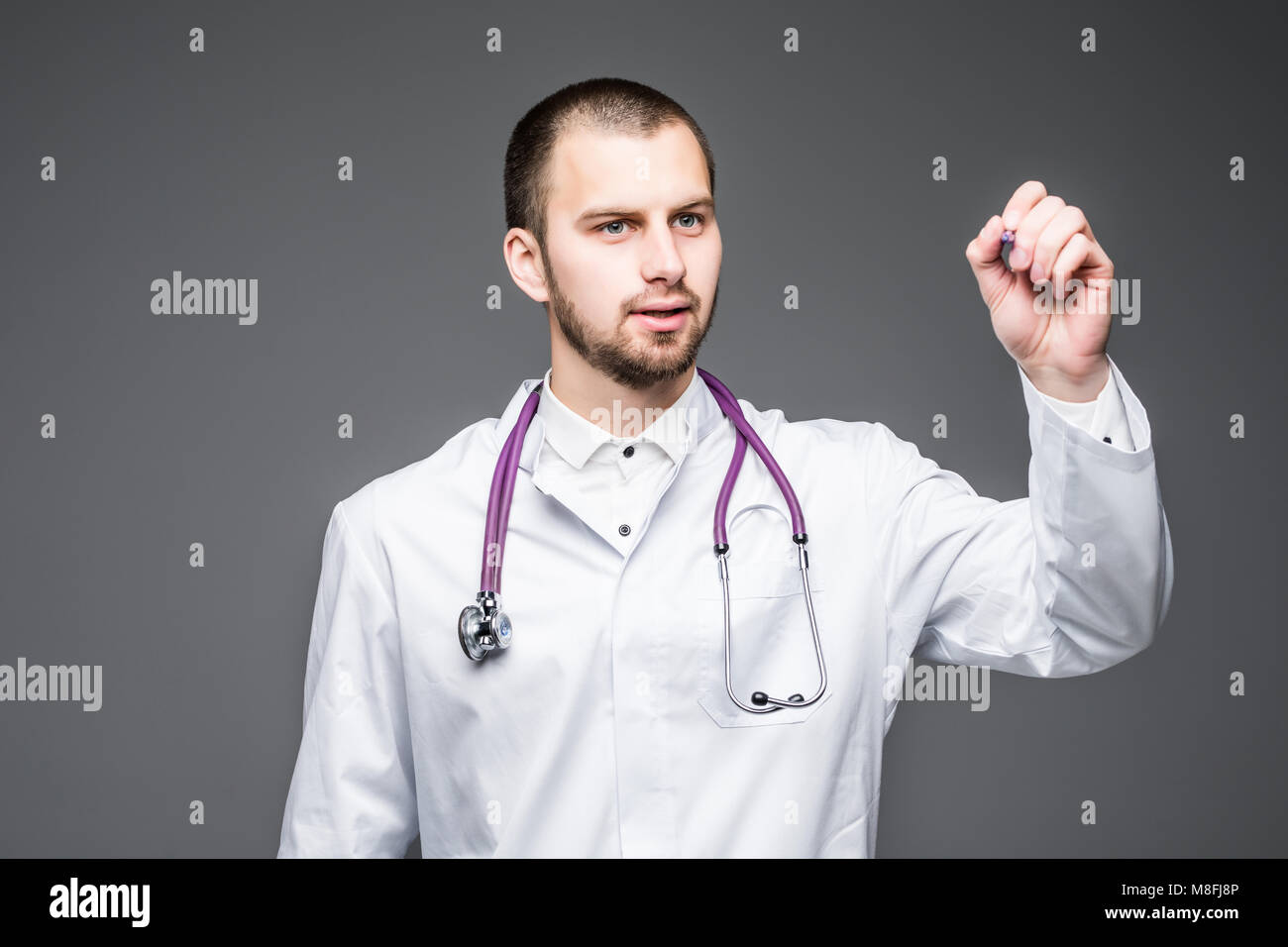 male doctor writing something on screen isolated over gray Stock Photo ...