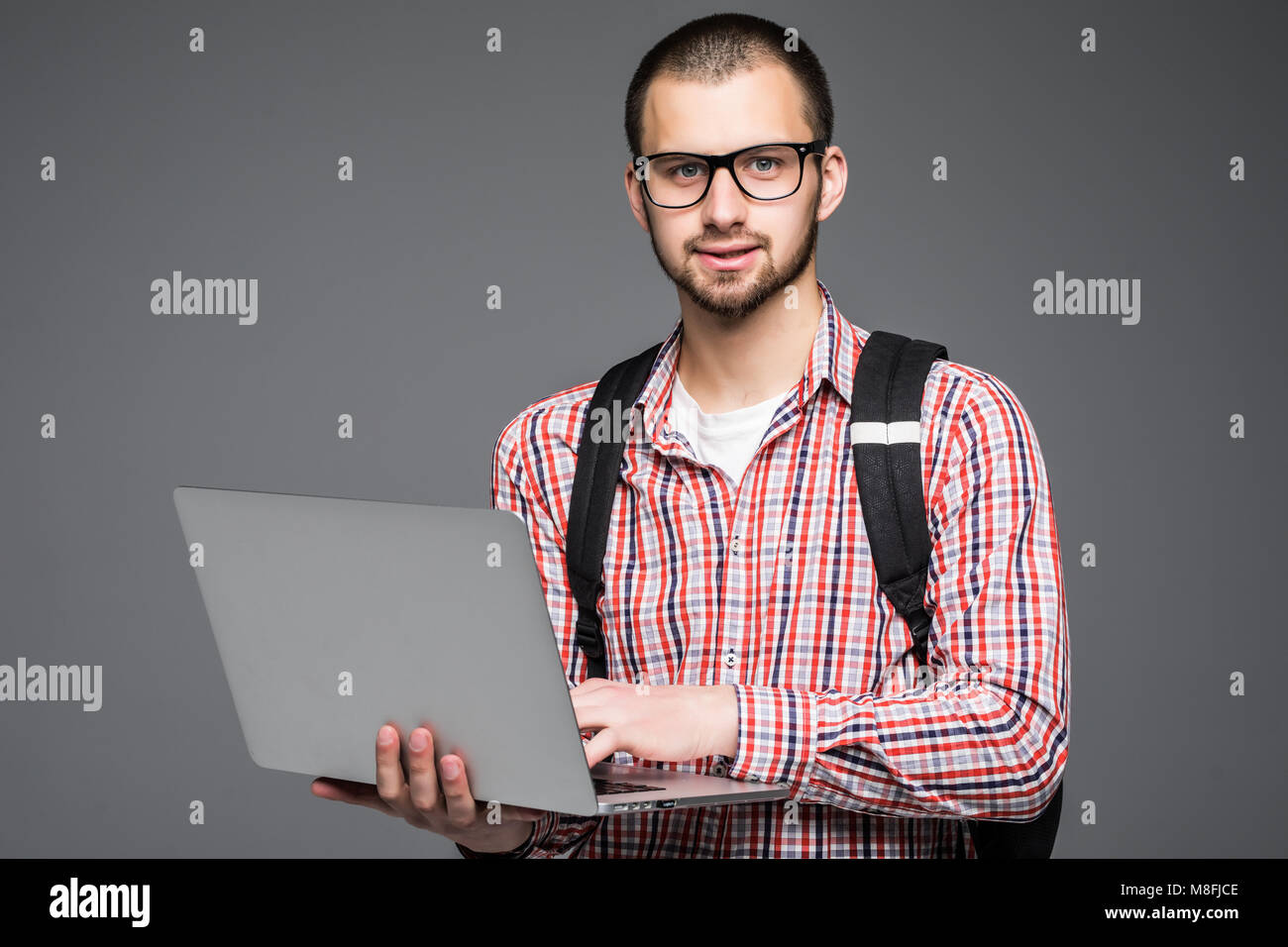 Young male student with laptop. isolated on gray background Stock Photo ...