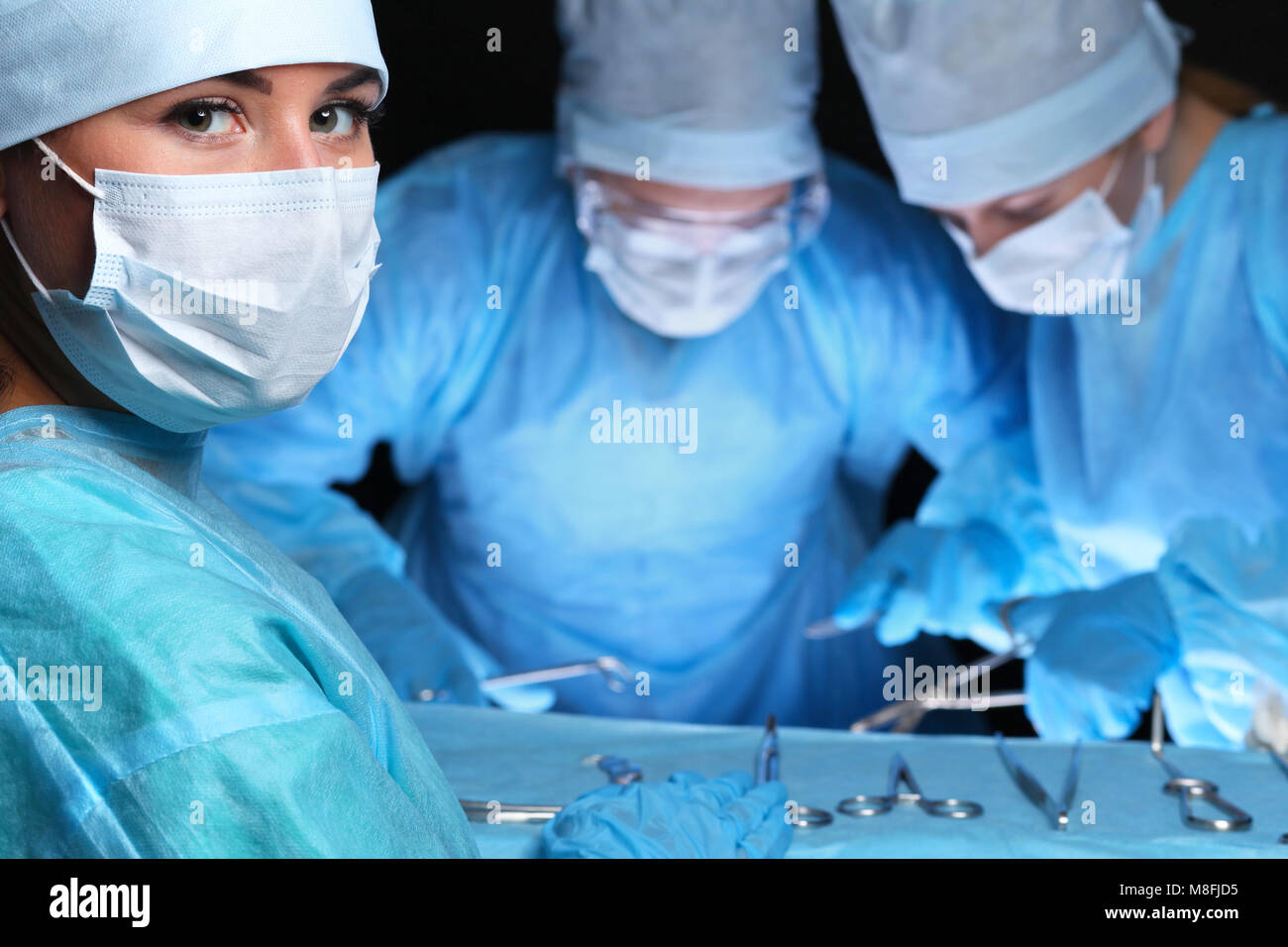 Closeup of surgeons performing operation. Focus on female nurse ...
