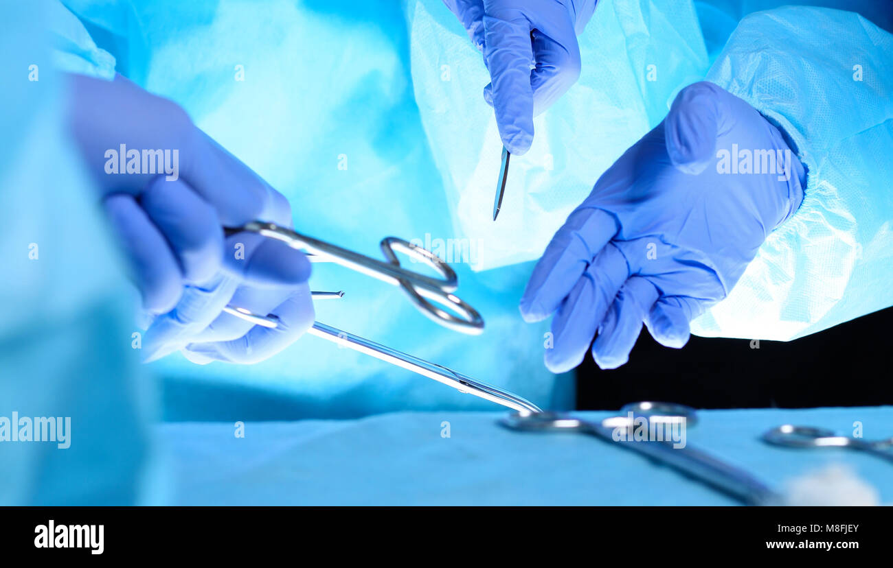 Surgeons hands holding surgical scissors and passing surgical equipment ...