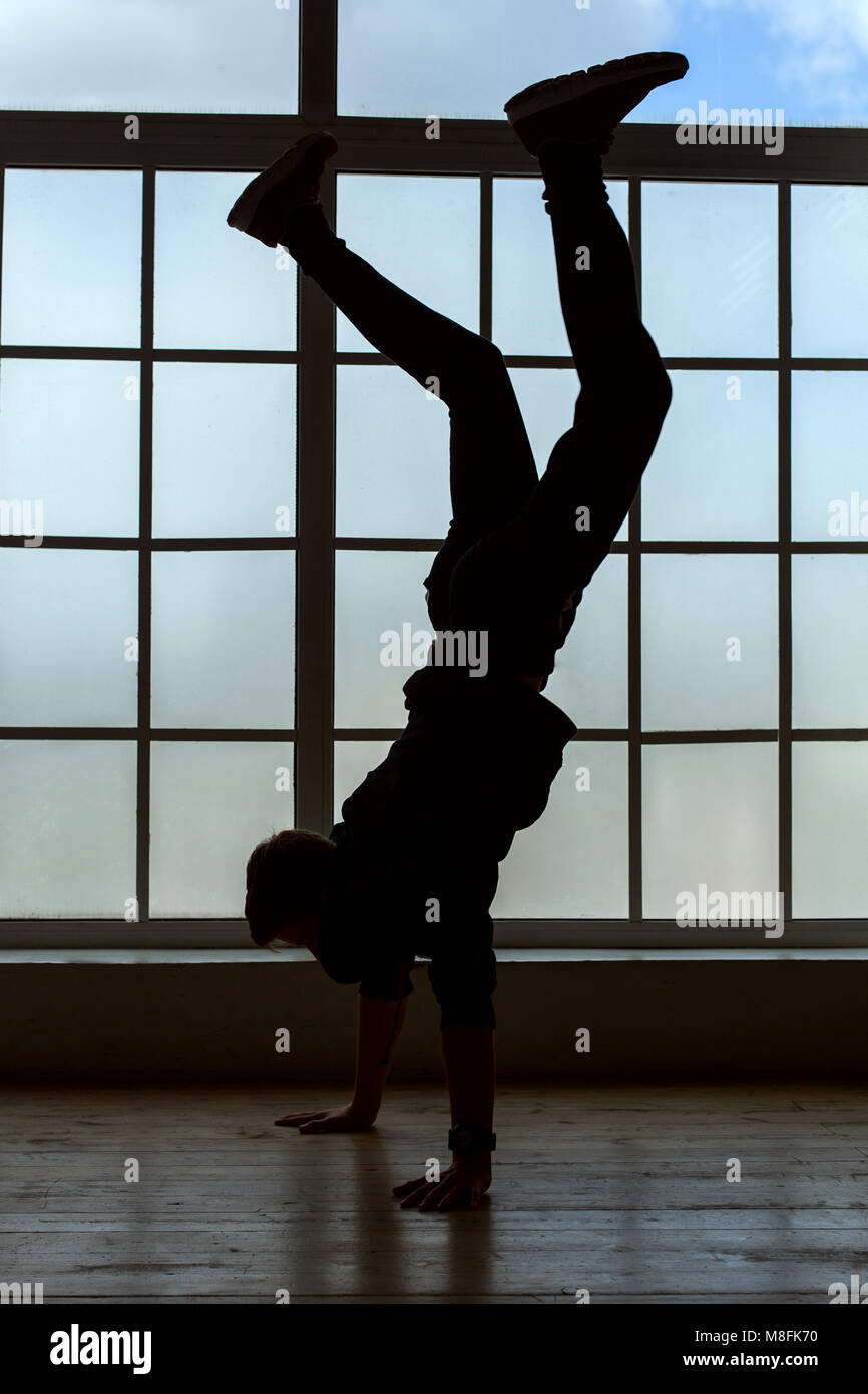 Silhouettes a young man. He makes a stand on his hands Stock Photo - Alamy