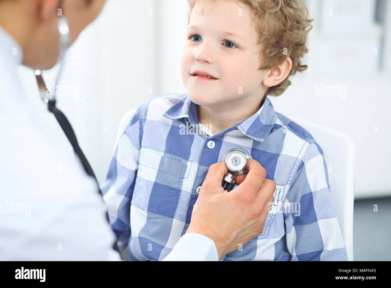Doctor and child patient. Physician examines little boy by stethoscope ...