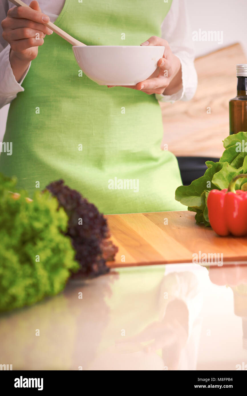 Close Up of human hands cooking vegetable salad in kitchen on the glass ...