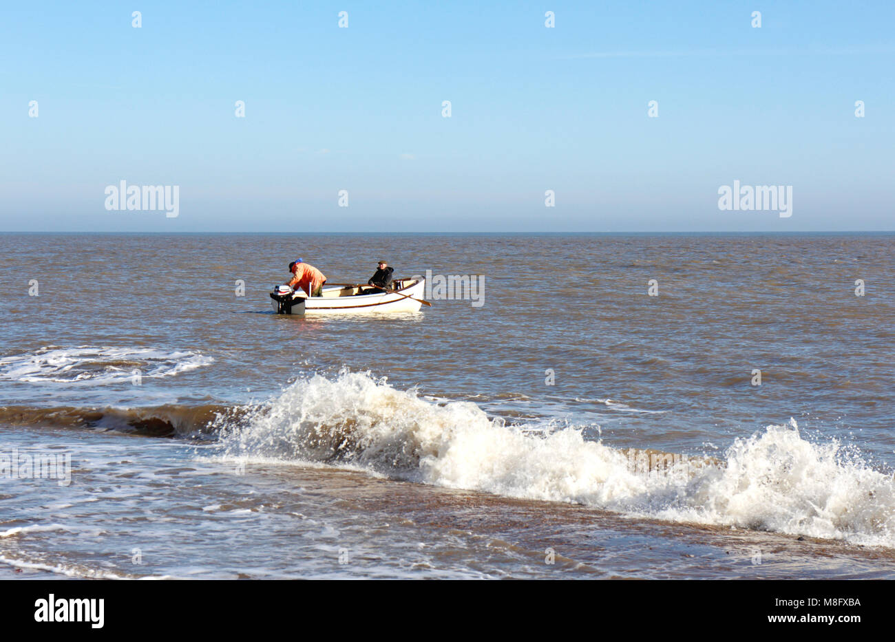 A small inshore fishing boat with two men aboard putting to sea on the ...