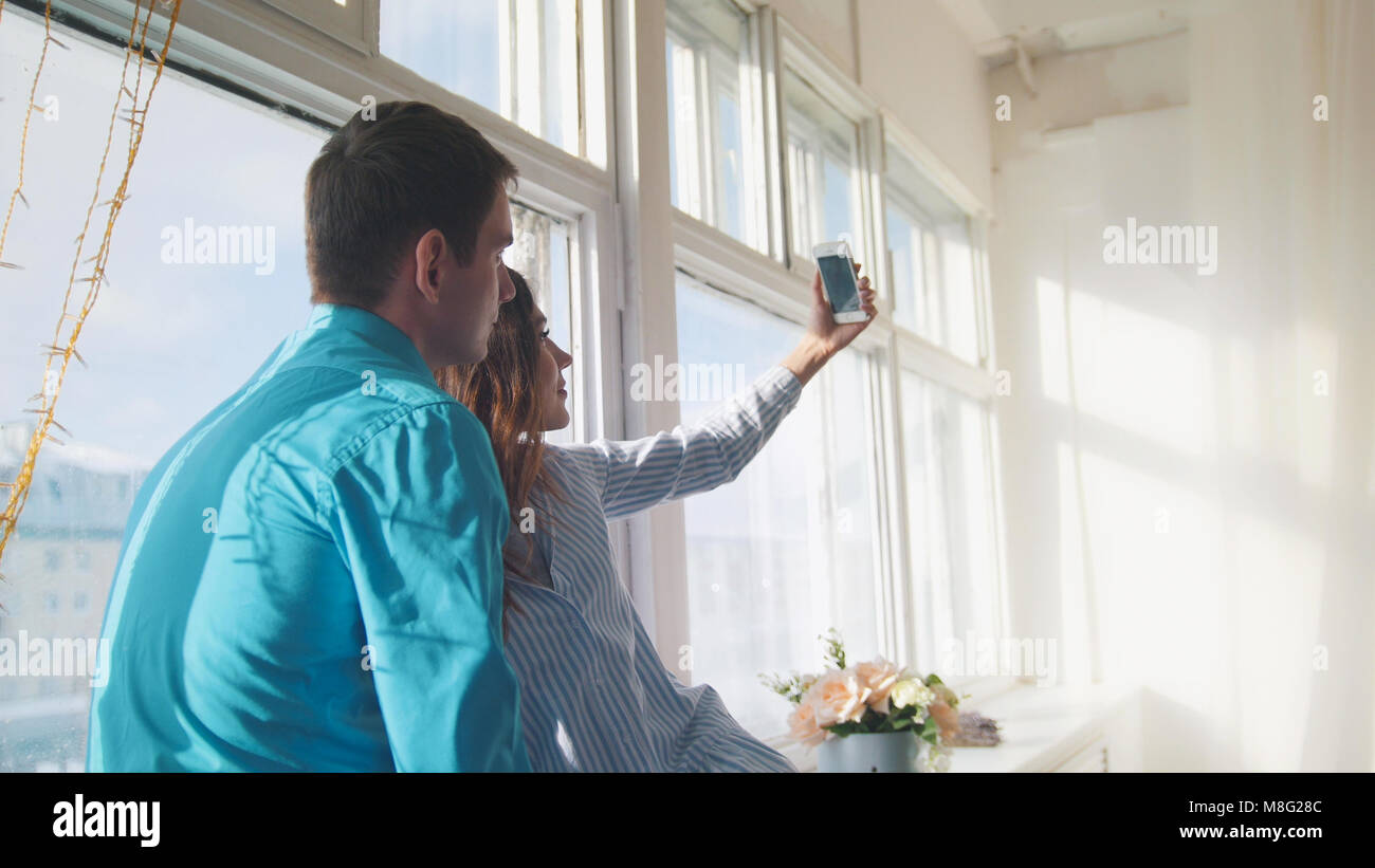 Happy cheerful loving couple making selfie on window, young attractive ...
