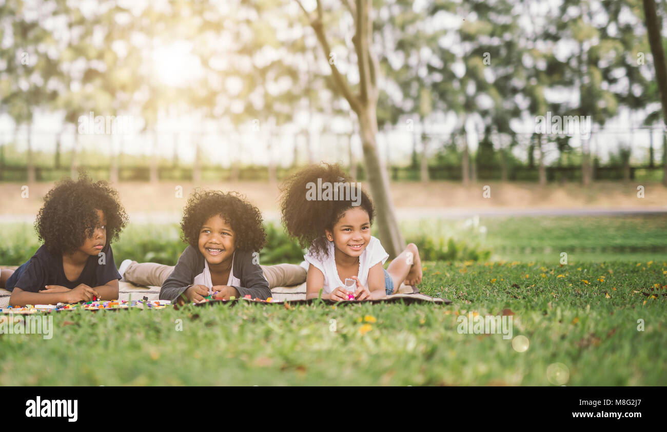 Happy three little friends laying on the grass in the park. american ...