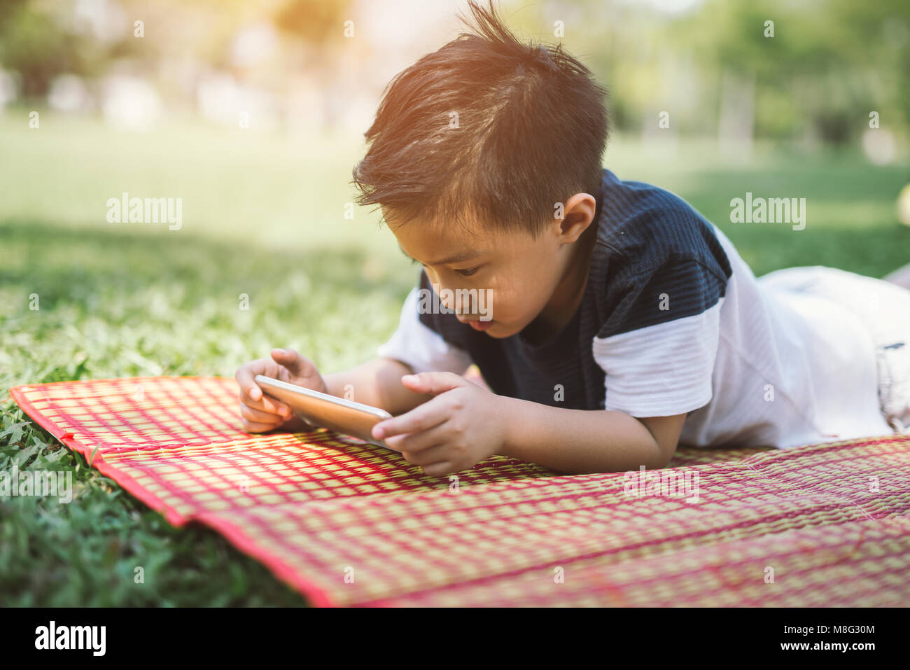 Kid palying smartphone in the park Stock Photo - Alamy