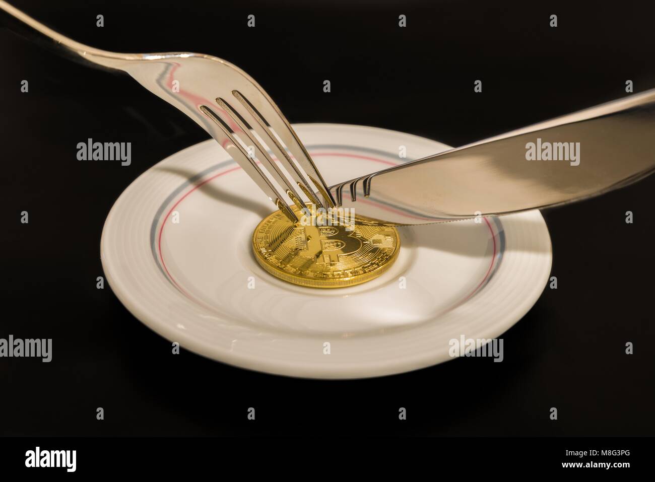 Gold coin bitcoin on plate with knife and fork isolated on black ...