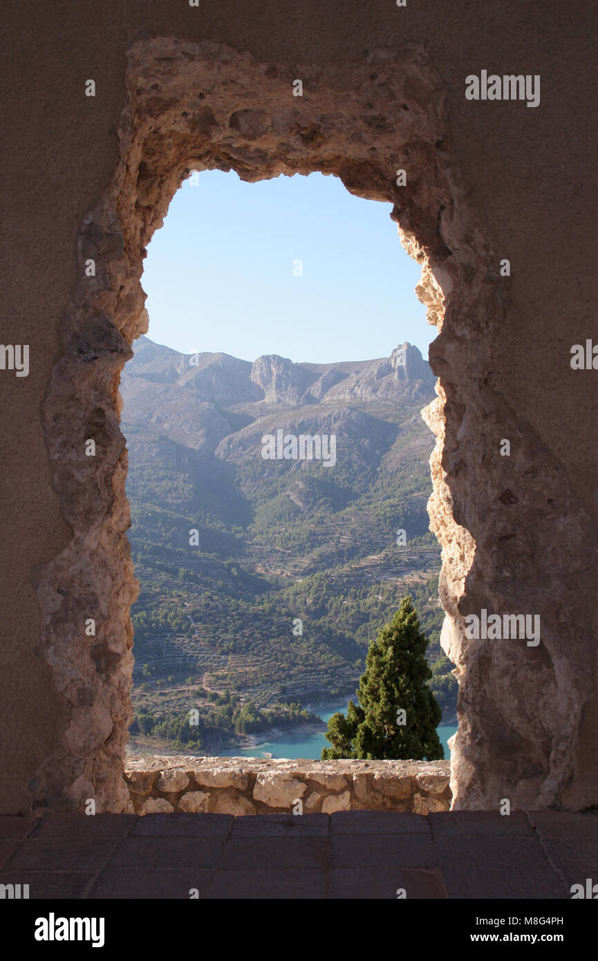 Mountains and lake viewed through a rough stone cave window. Alicante ...