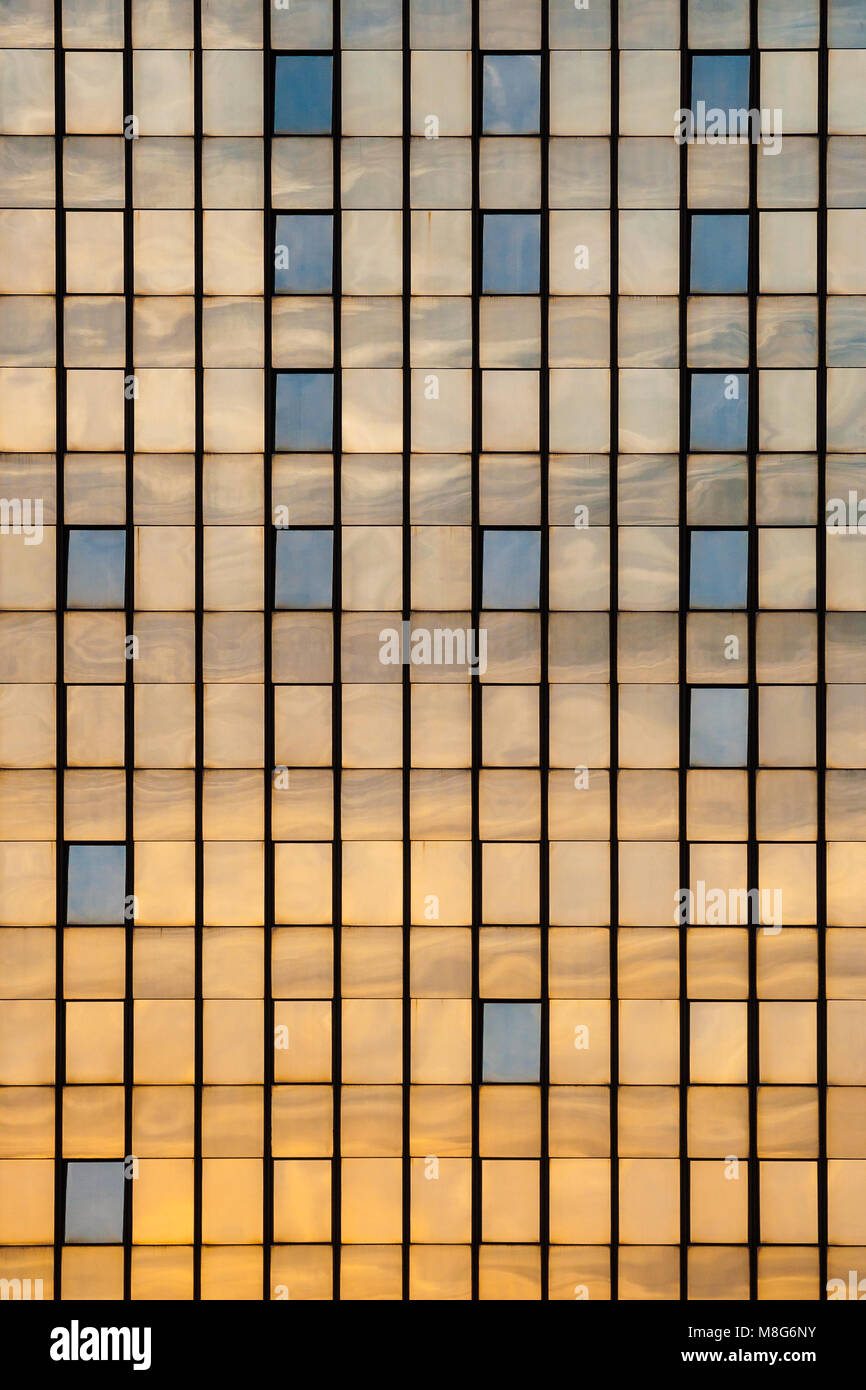 Side of a glass tower building with sky and sun reflecting on its ...