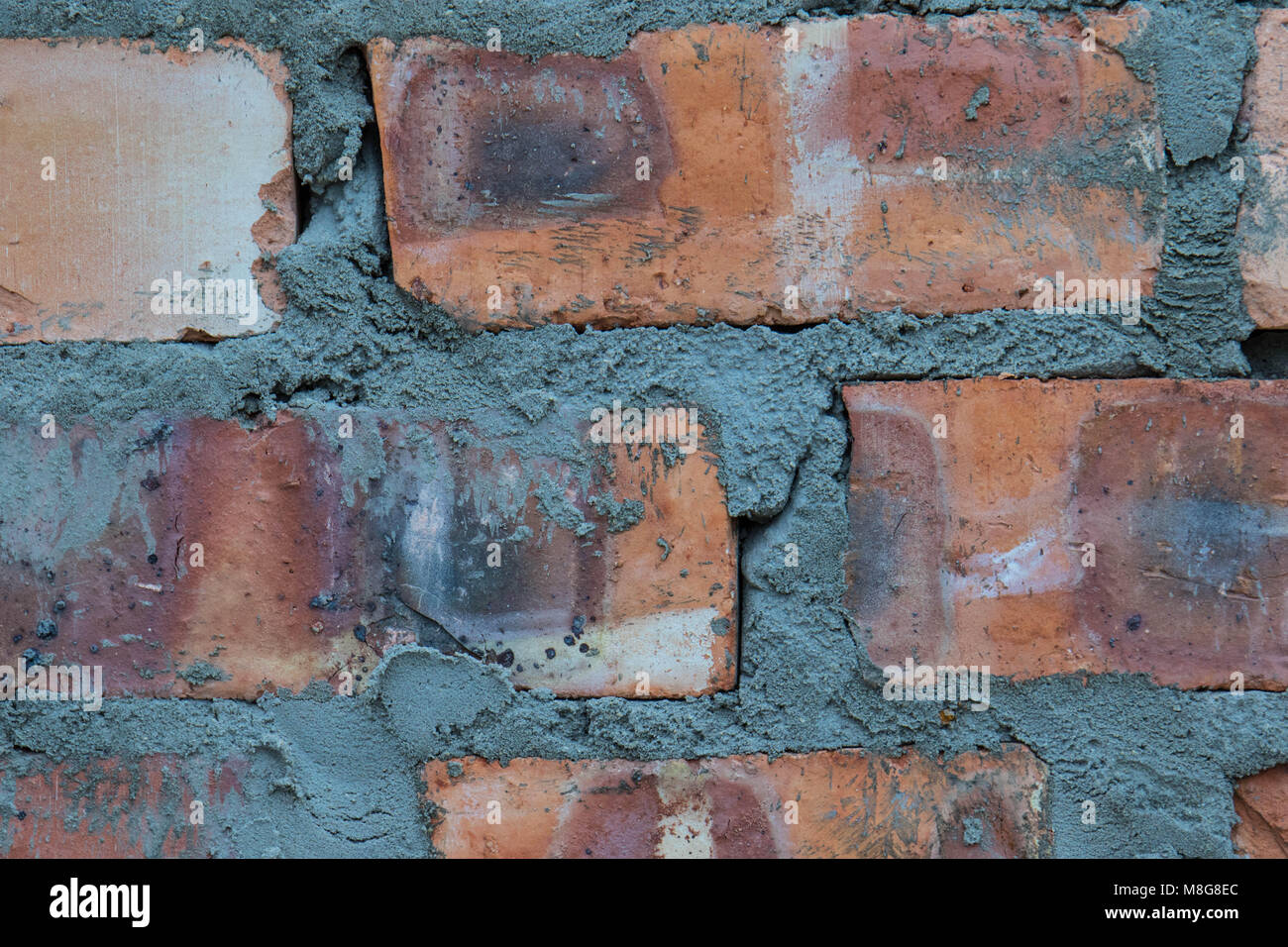 Background use a raw brick wall with red bricks and grey cement image ...