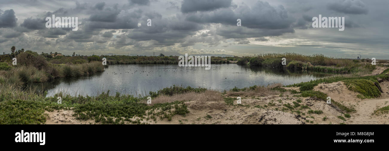 Panoramic scene of rain clouds beginning to form over reflective water ...