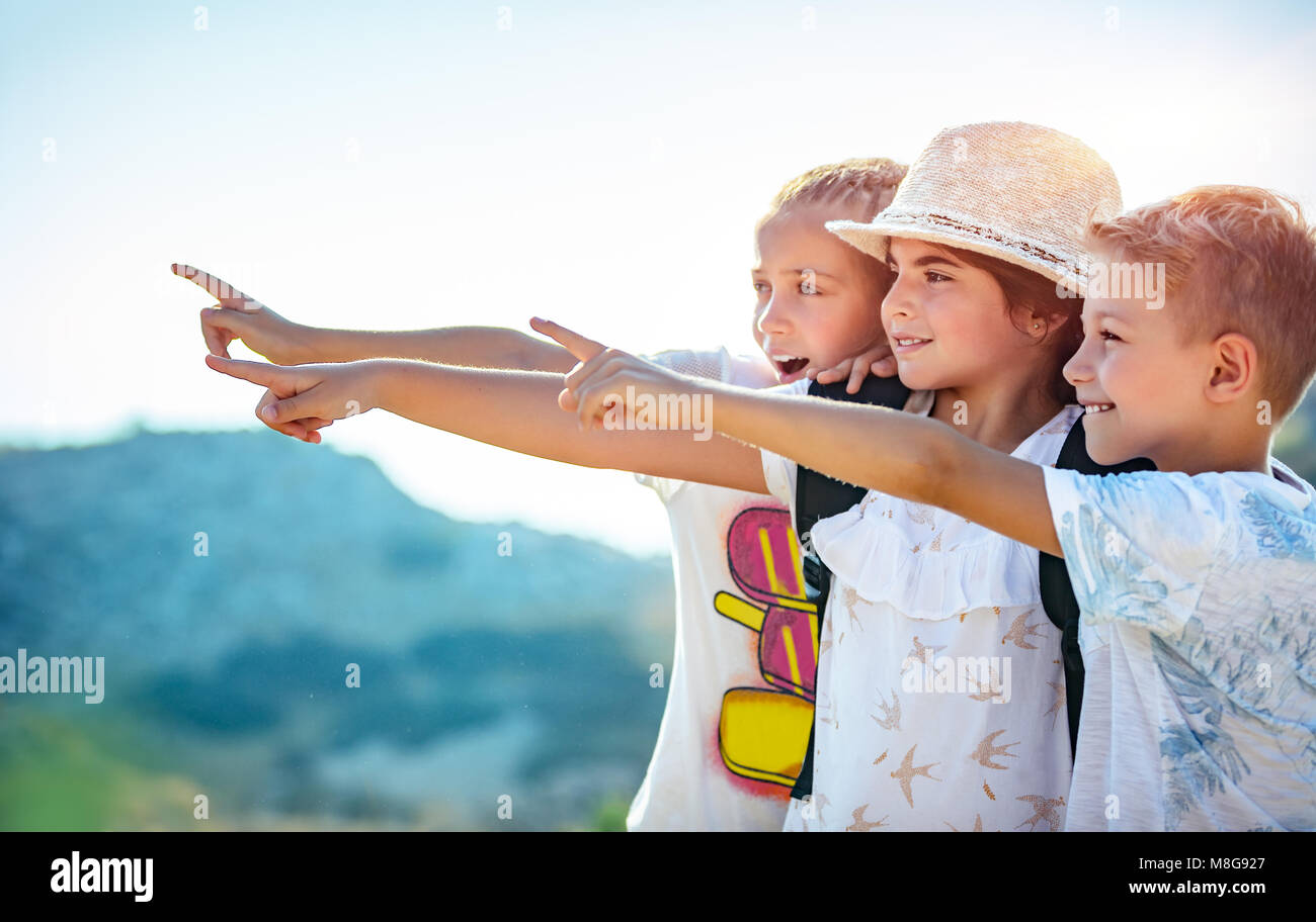 Portrait of a three happy friends outdoors, kids with wonder looking at ...