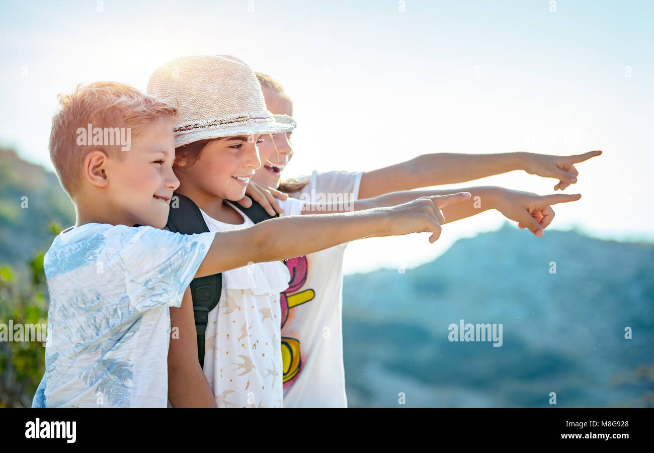 Portrait of a three happy friends outdoors, kids with wonder looking at ...