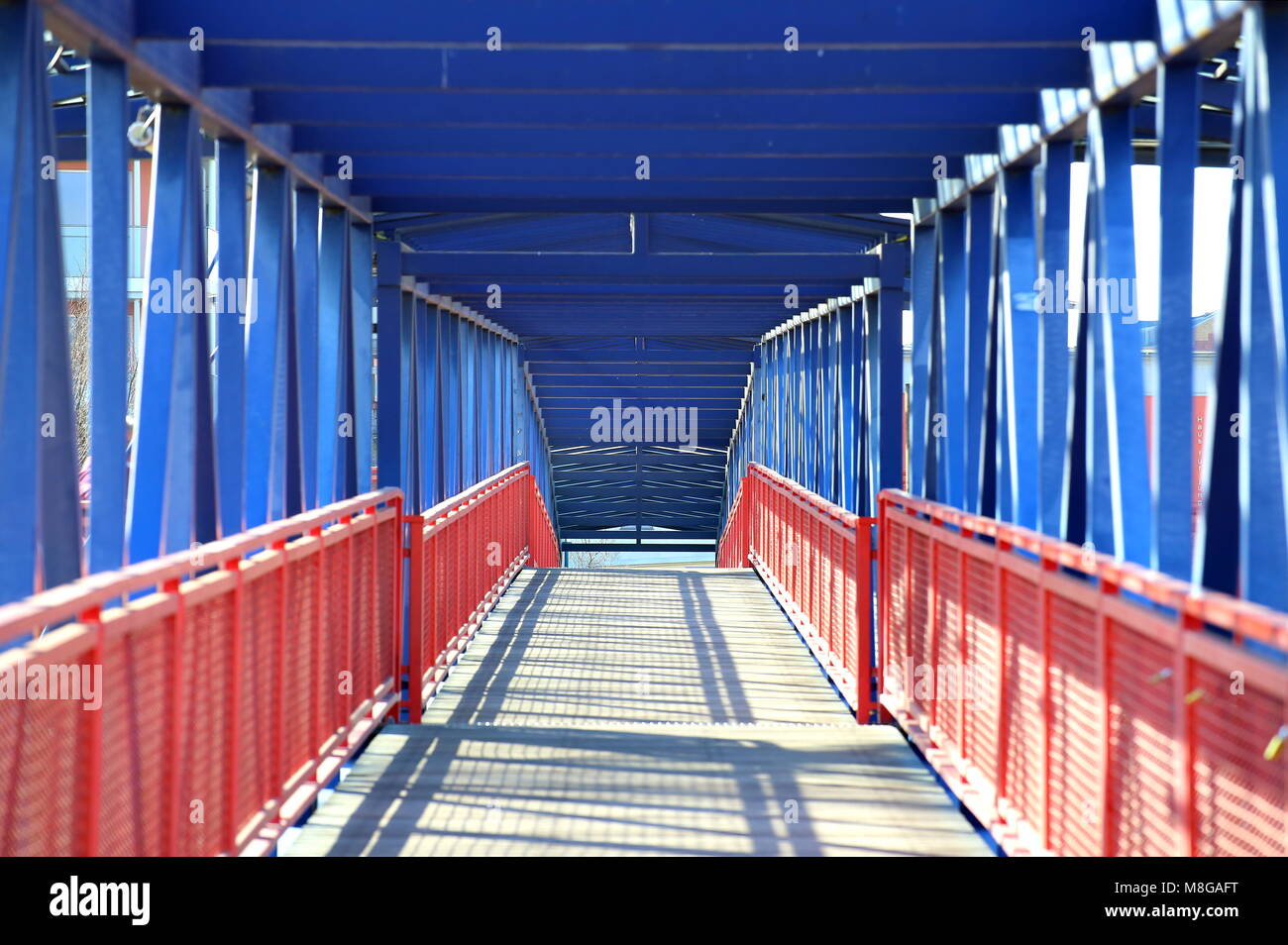 Passage through a steel bridge with red and blue parts Stock Photo - Alamy