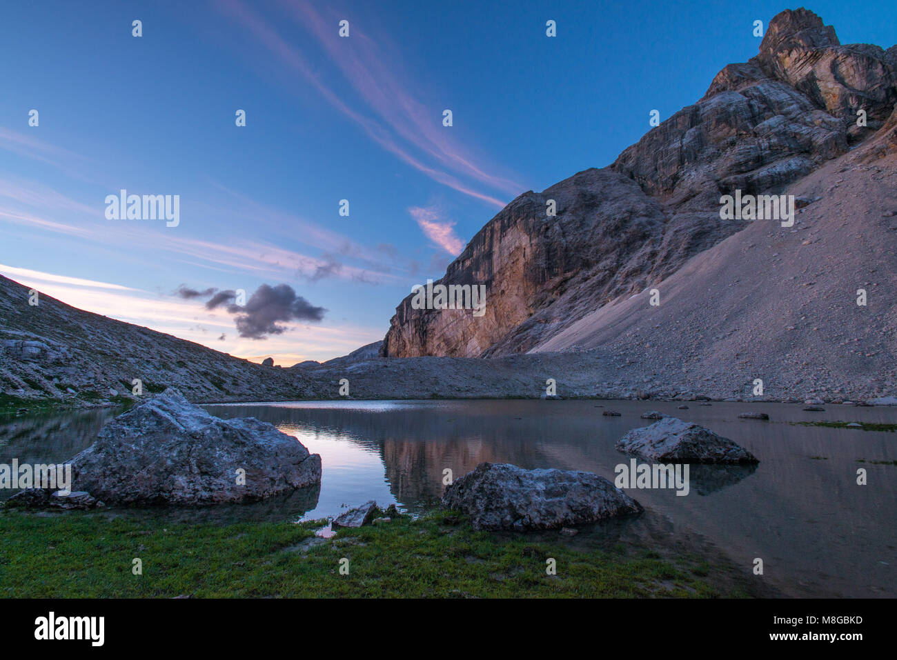 Wonderful alpine lake, pond reflecting mountains while a painted sky ...