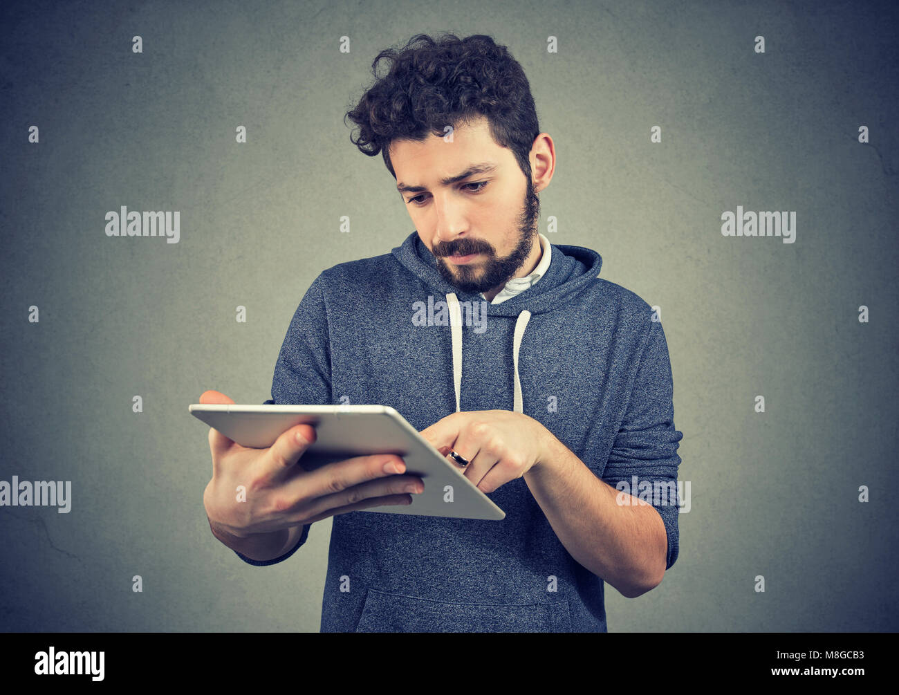 Young hipster smart man using modern tablet looking interested ...