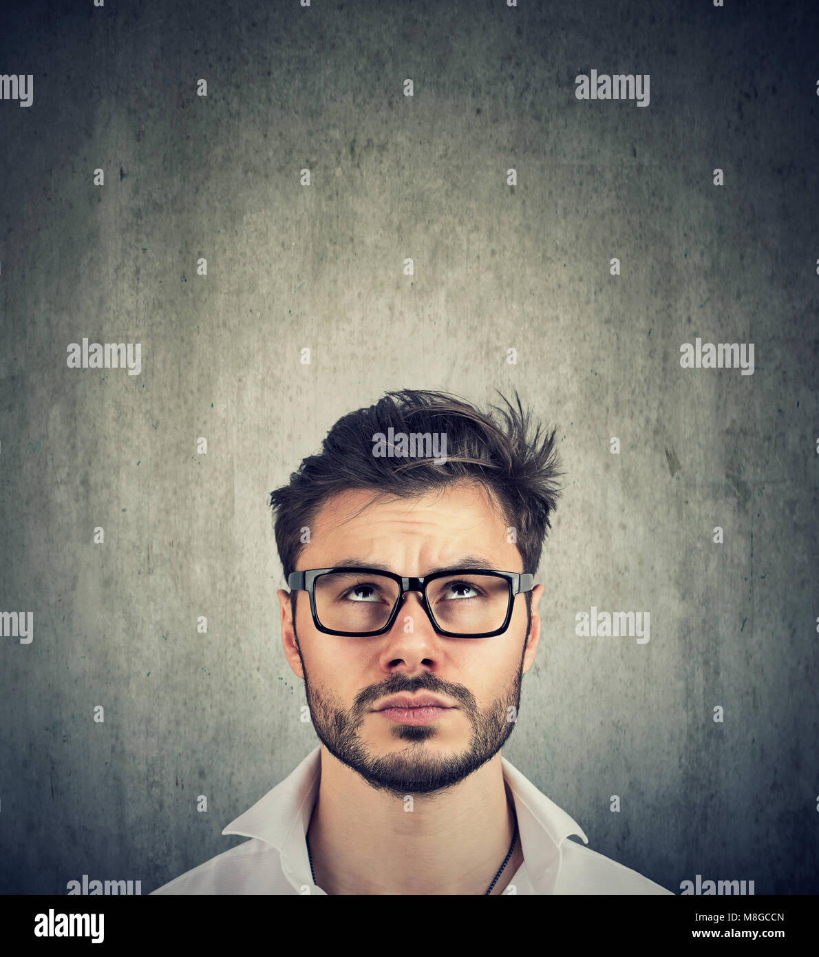 portrait of a young doubtful man with glasses looking up Stock Photo ...