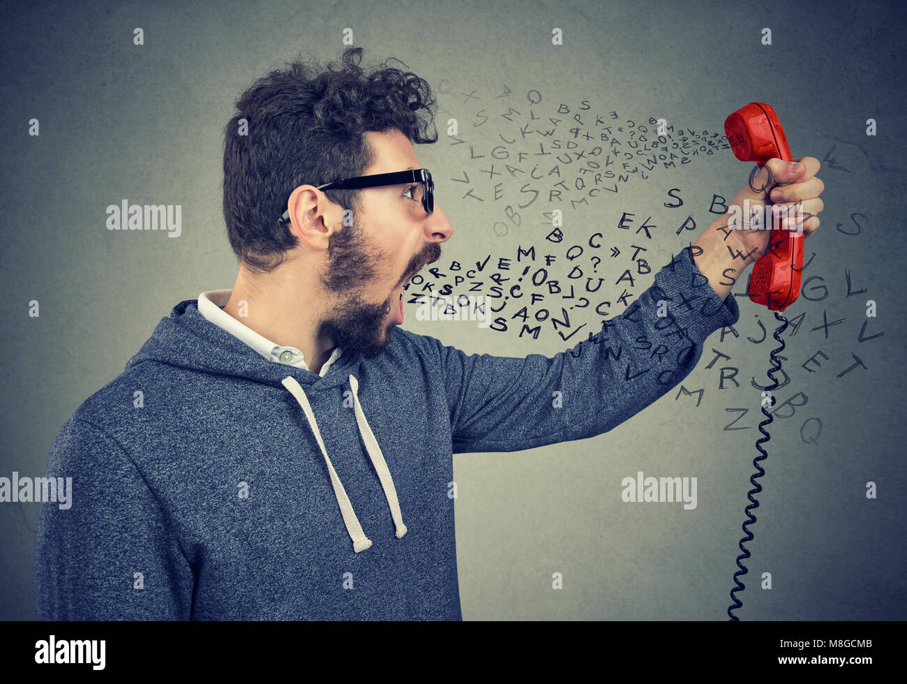 Side profile of an angry man screaming at someone on telephone handset ...