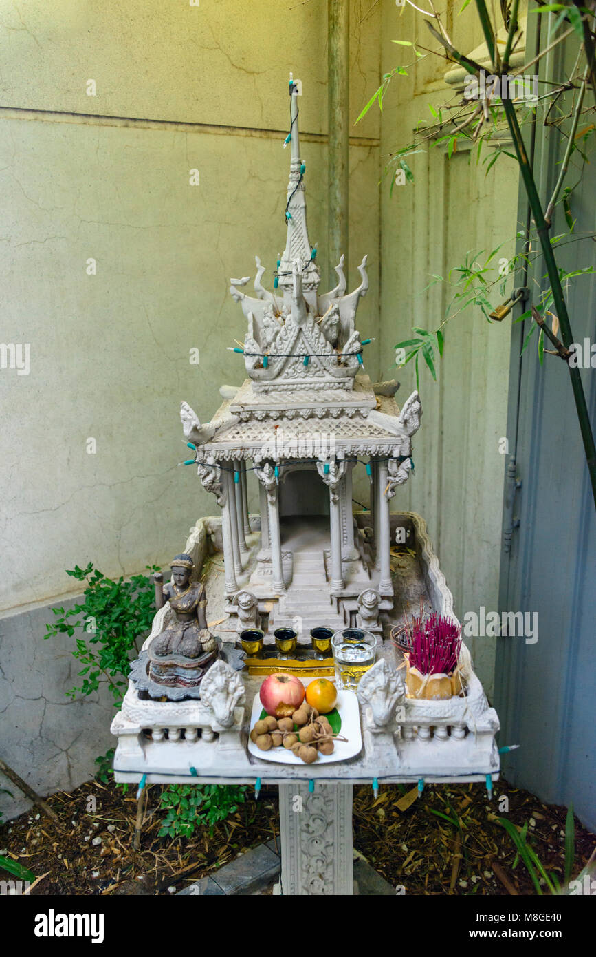 Small white stone Buddhist shrine with offerings of fruit and incense ...