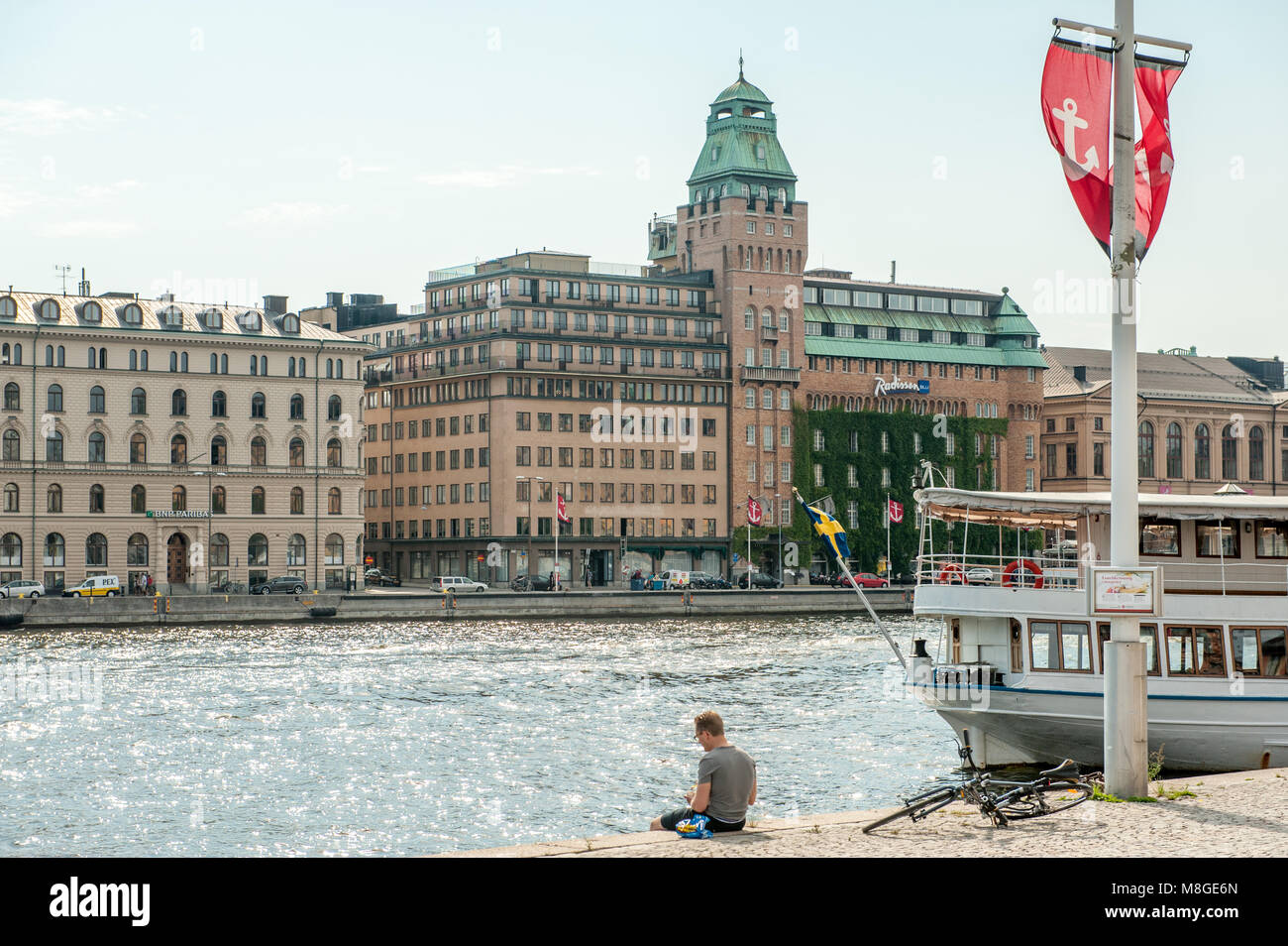 Young man enjoys a picnic at Nybroviken waterfront in Stockholm. The ...