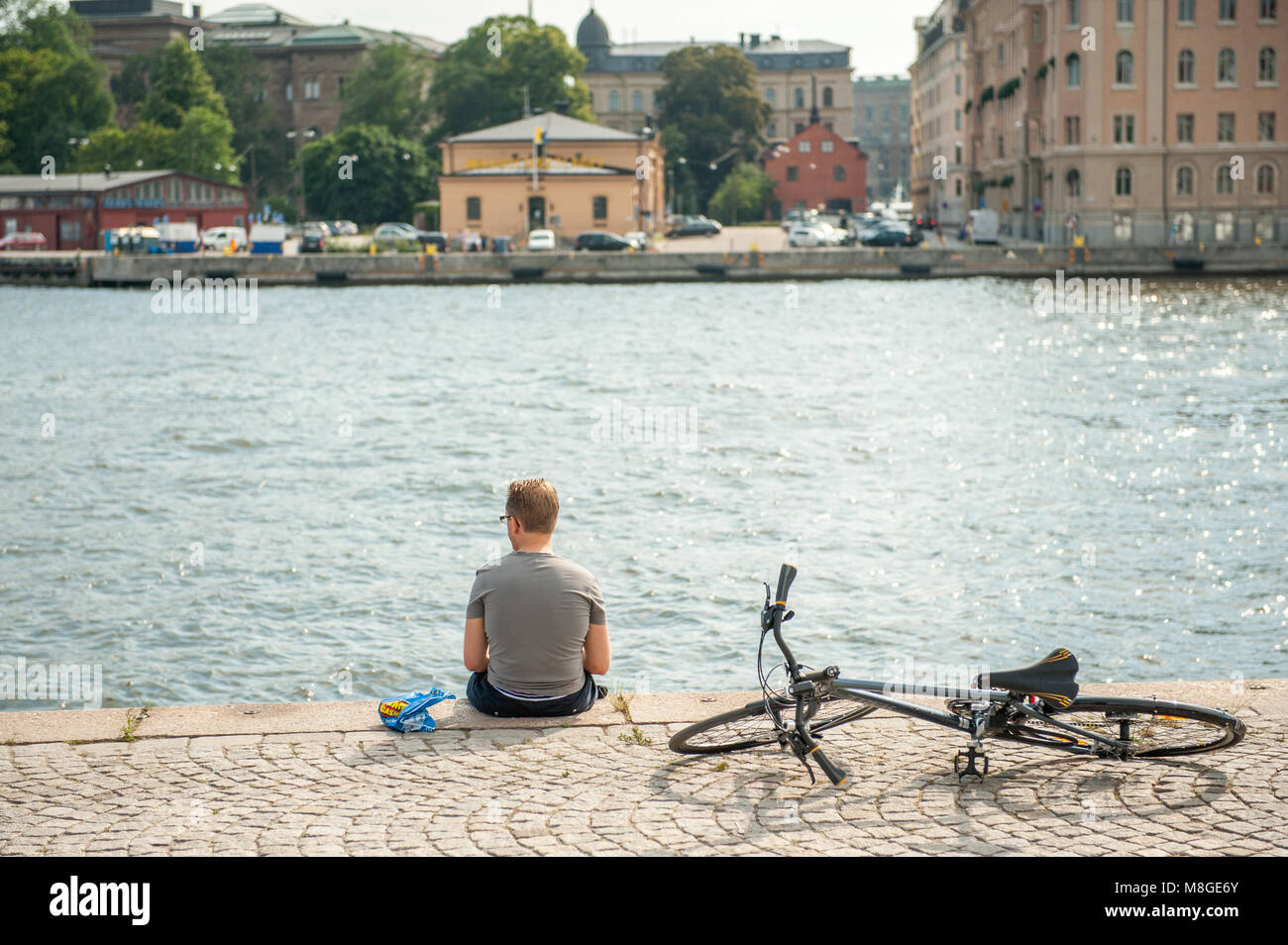 Young man enjoys a picnic at Nybroviken waterfront in Stockholm. The ...