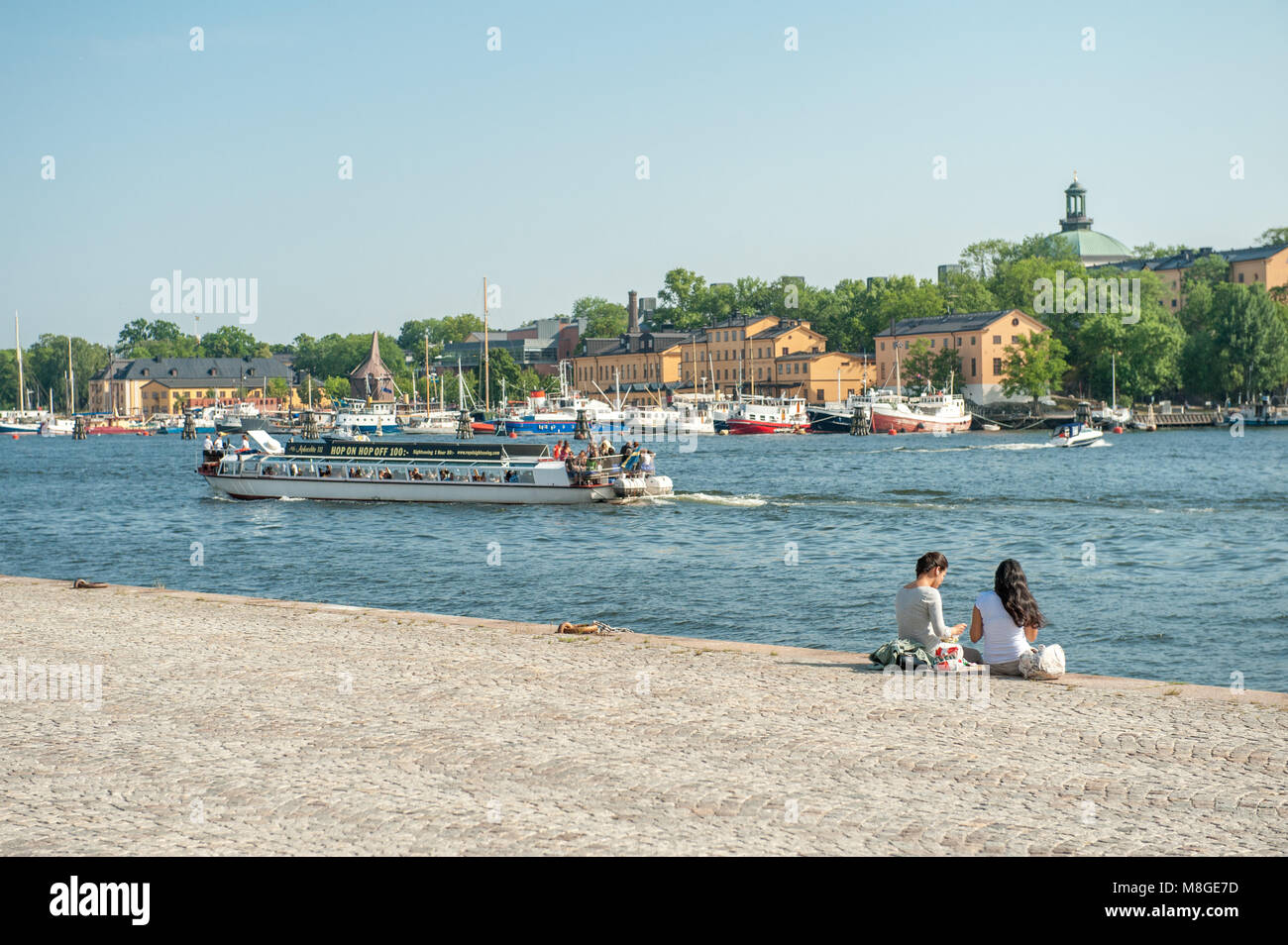 Tourists enjoy a picnic at Nybroviken waterfront in Stockholm. The city ...