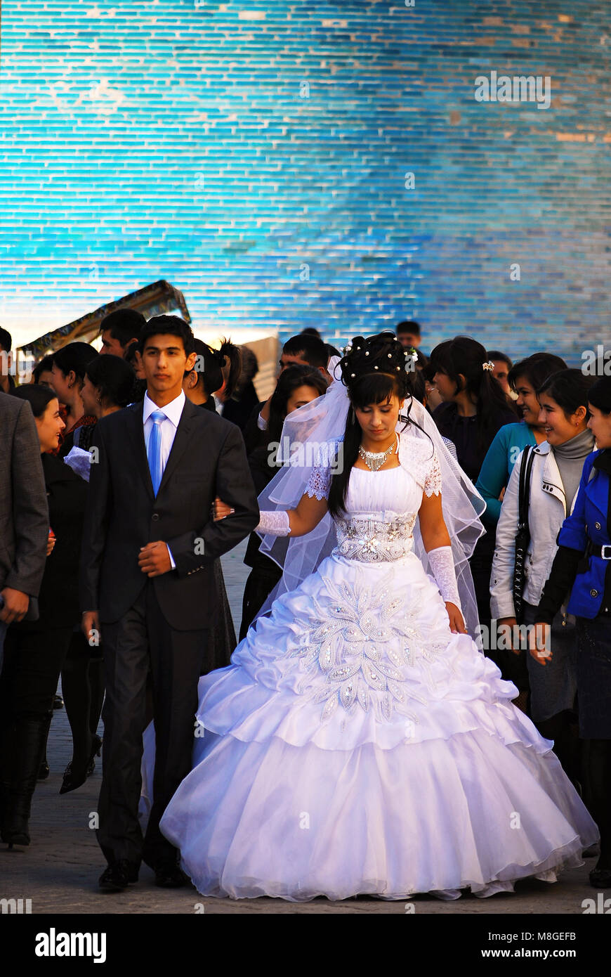 Young Uzbek couple in Khiva after getting married. Wedding party keeps ...