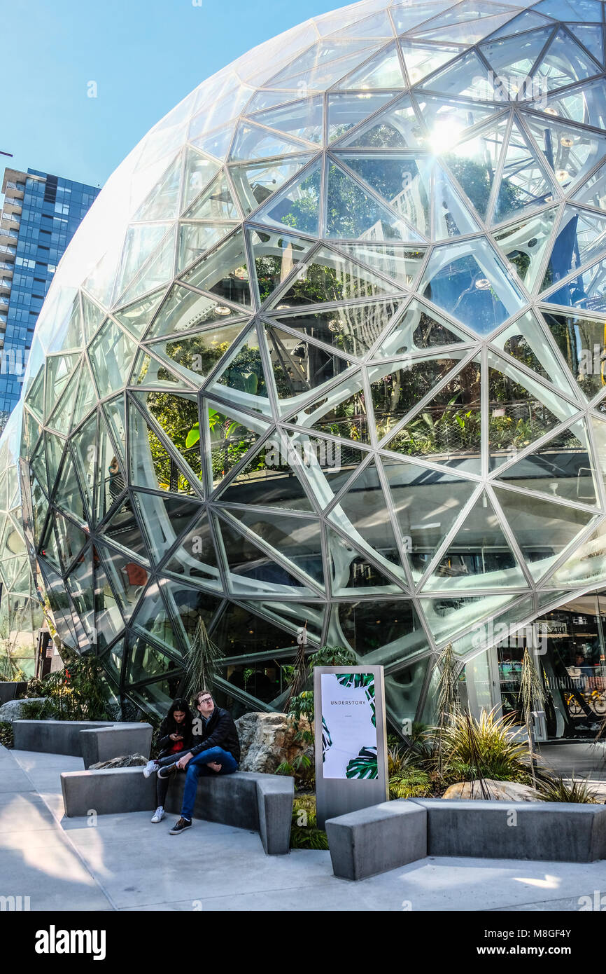 Two people sit in front of the glass dome Spheres at Amazon headquarter ...