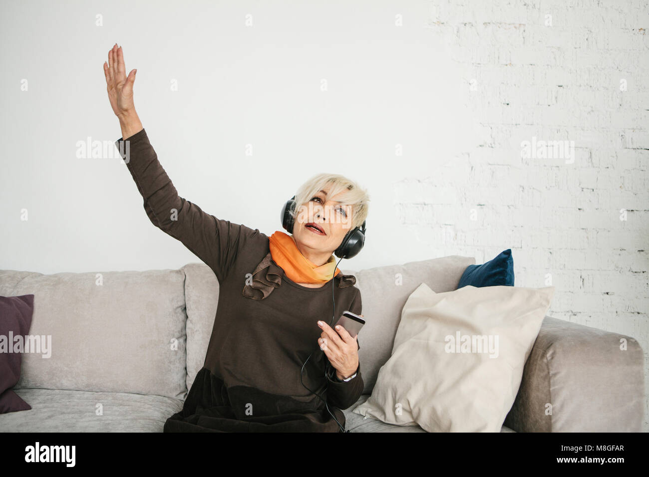 A positive elderly woman listens to music and sings. The older ...