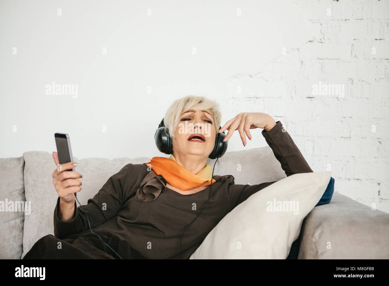 A positive elderly woman listens to music and sings. The older ...
