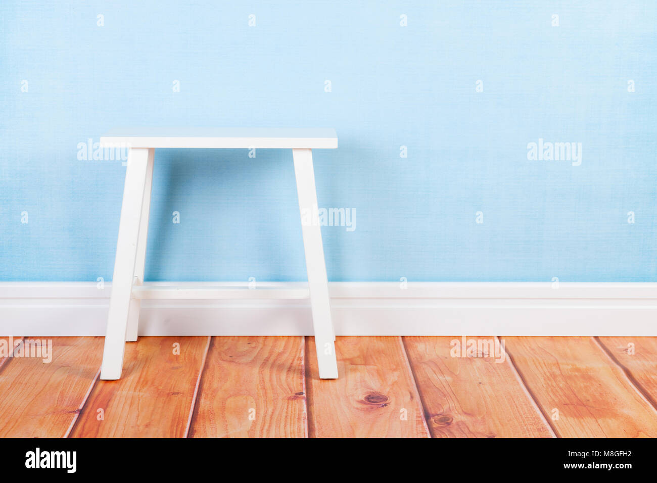 Little white table in interieur with blue wall paper Stock Photo - Alamy