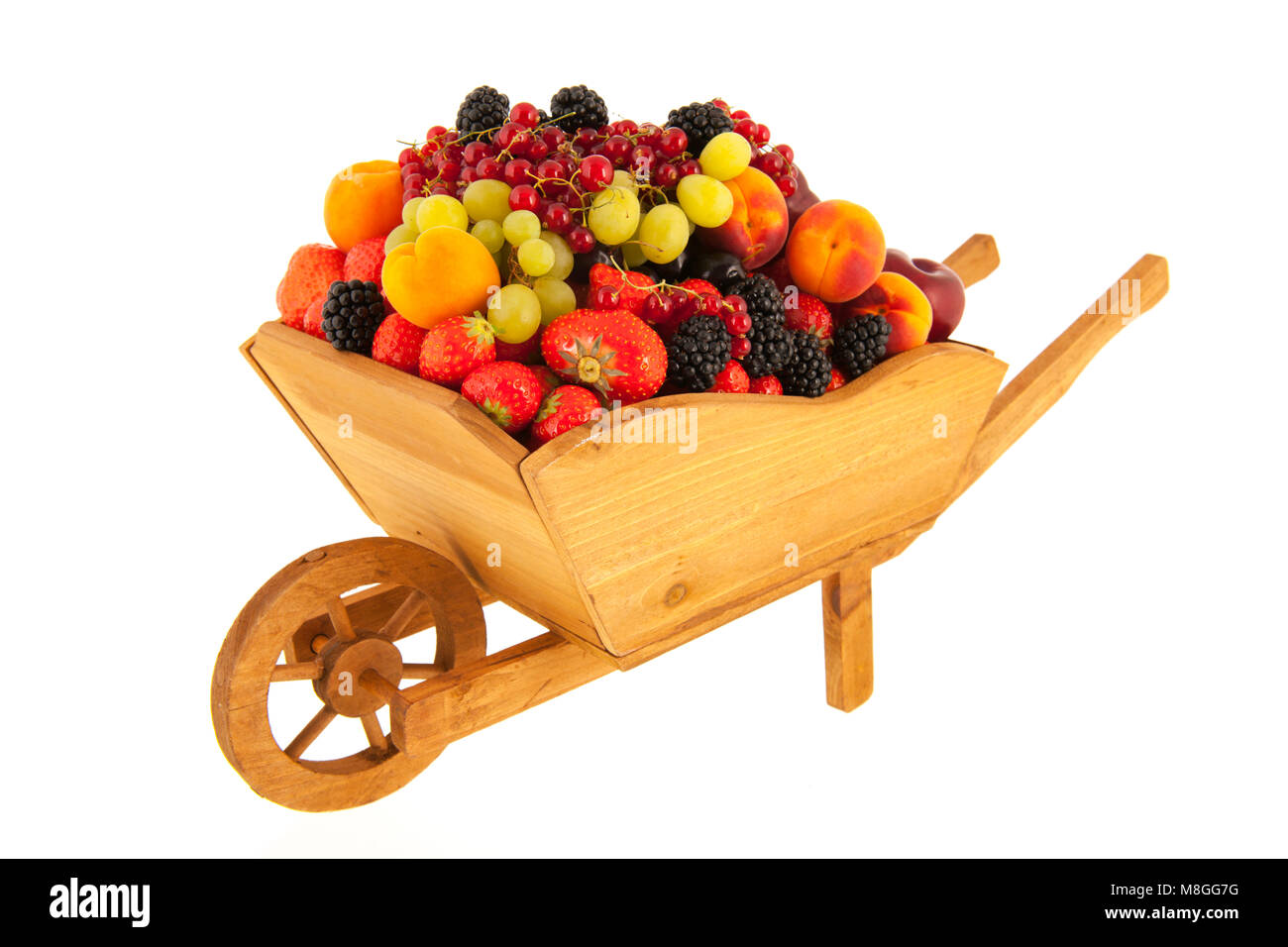 Wooden wheel barrow with fresh summer fruit isolated over white ...