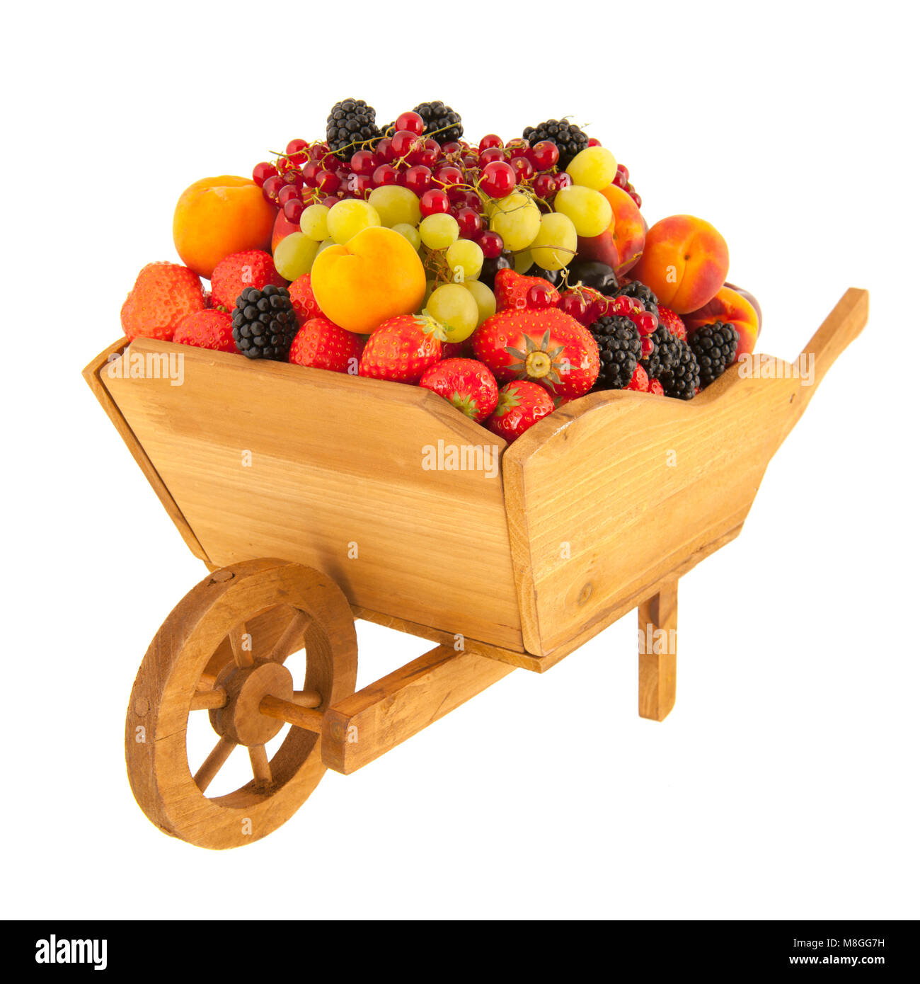 Wooden wheel barrow with fresh summer fruit isolated over white ...